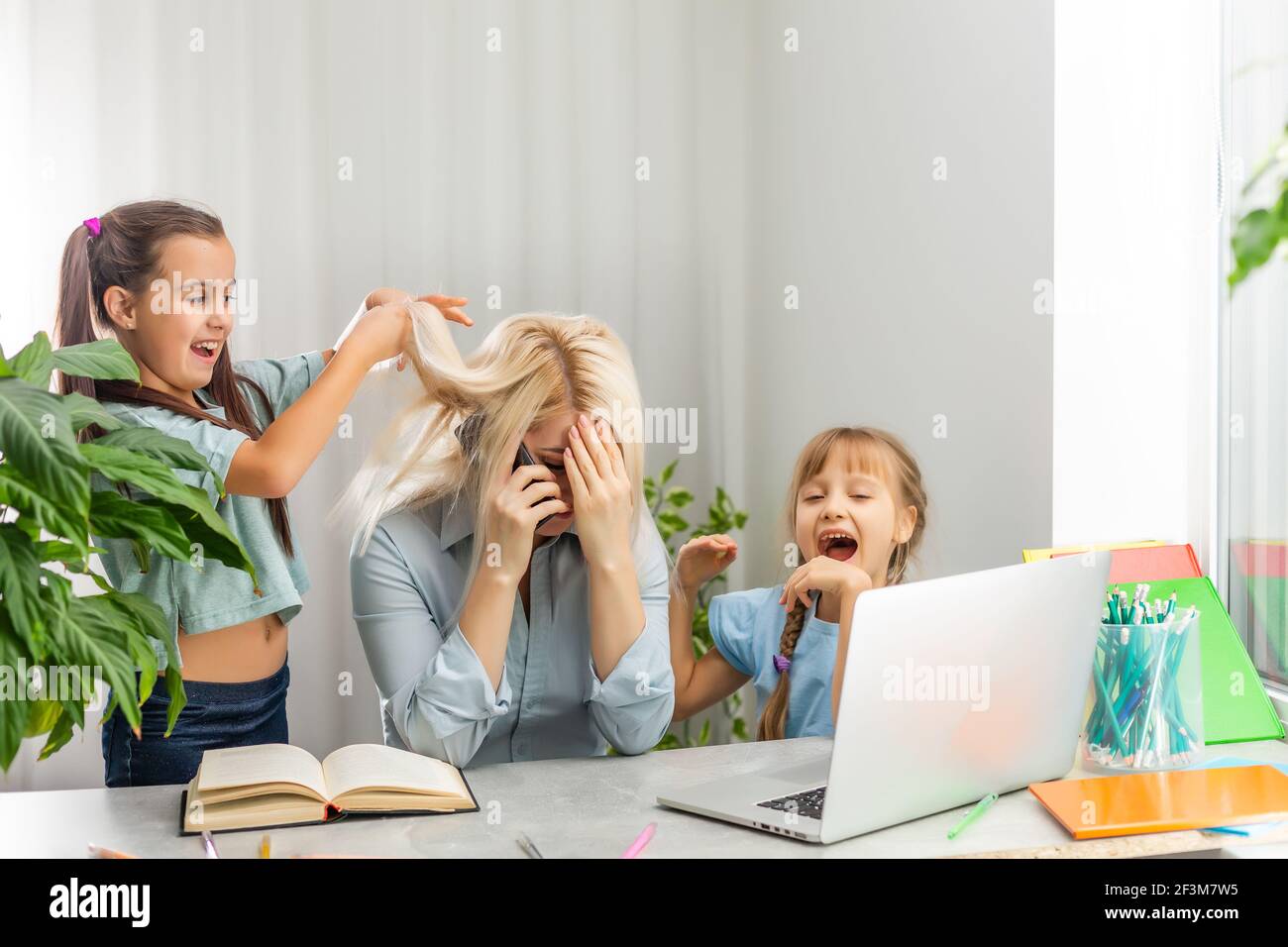 A young mother with two children works from home on a computer. Fatigue ...