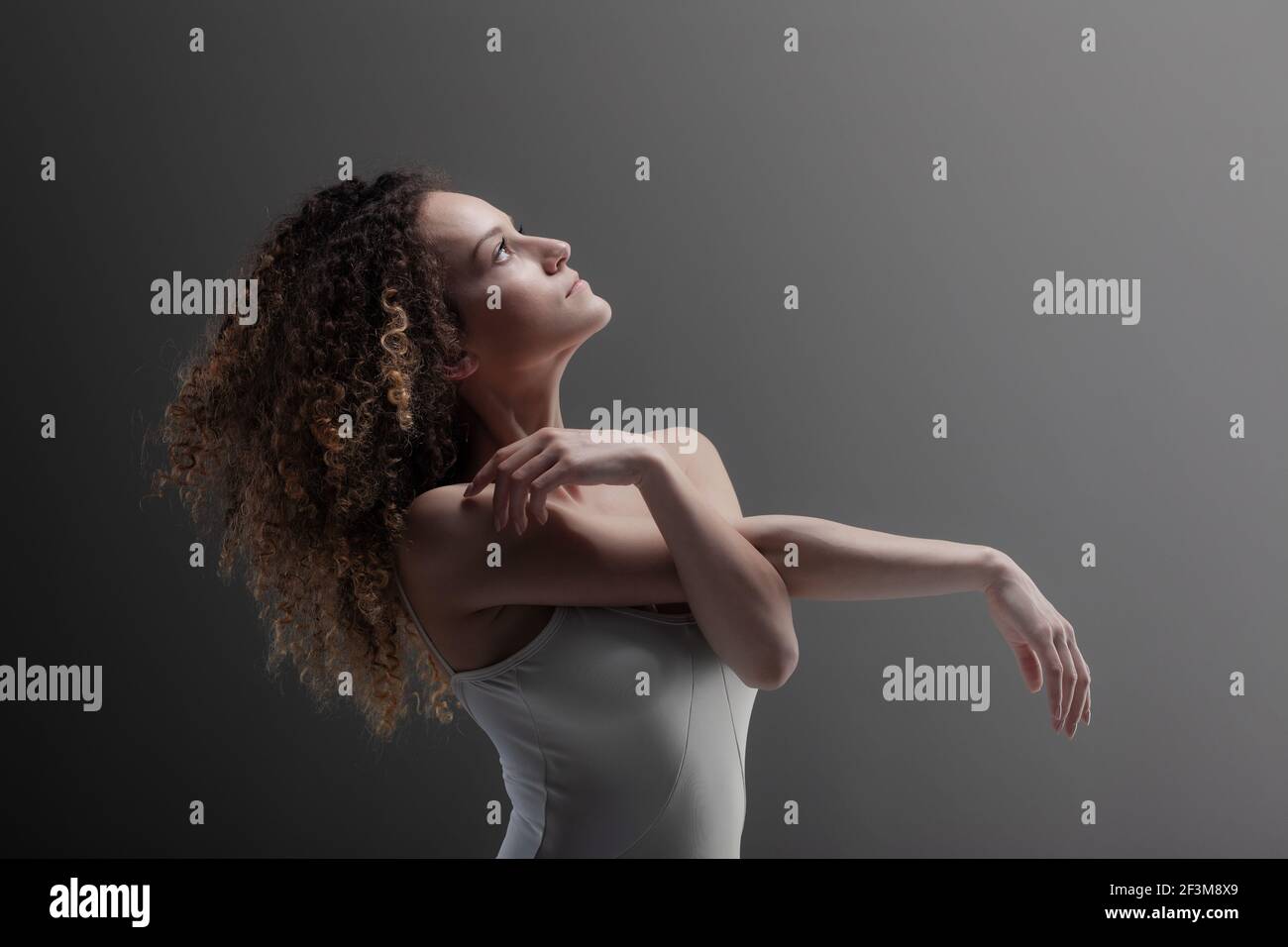 Girl with curly hair making ballet poses. Ballerina in white dress ...