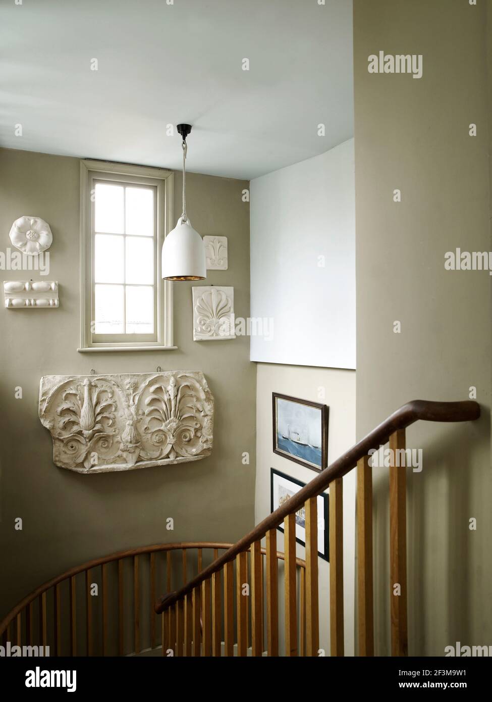 Wooden banister of staircase with wall mounted artwork and window in ...