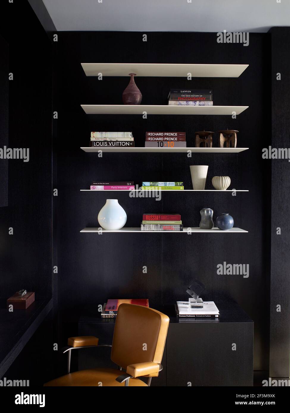 Corner of study area with floating shelves on black walls holding books ...