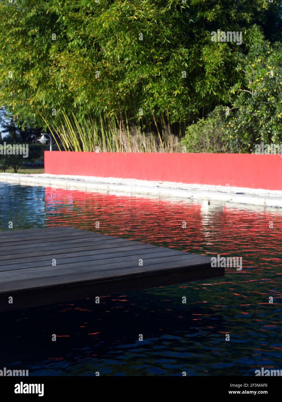 Wooden pier over water with red painted wall in French villa Stock ...