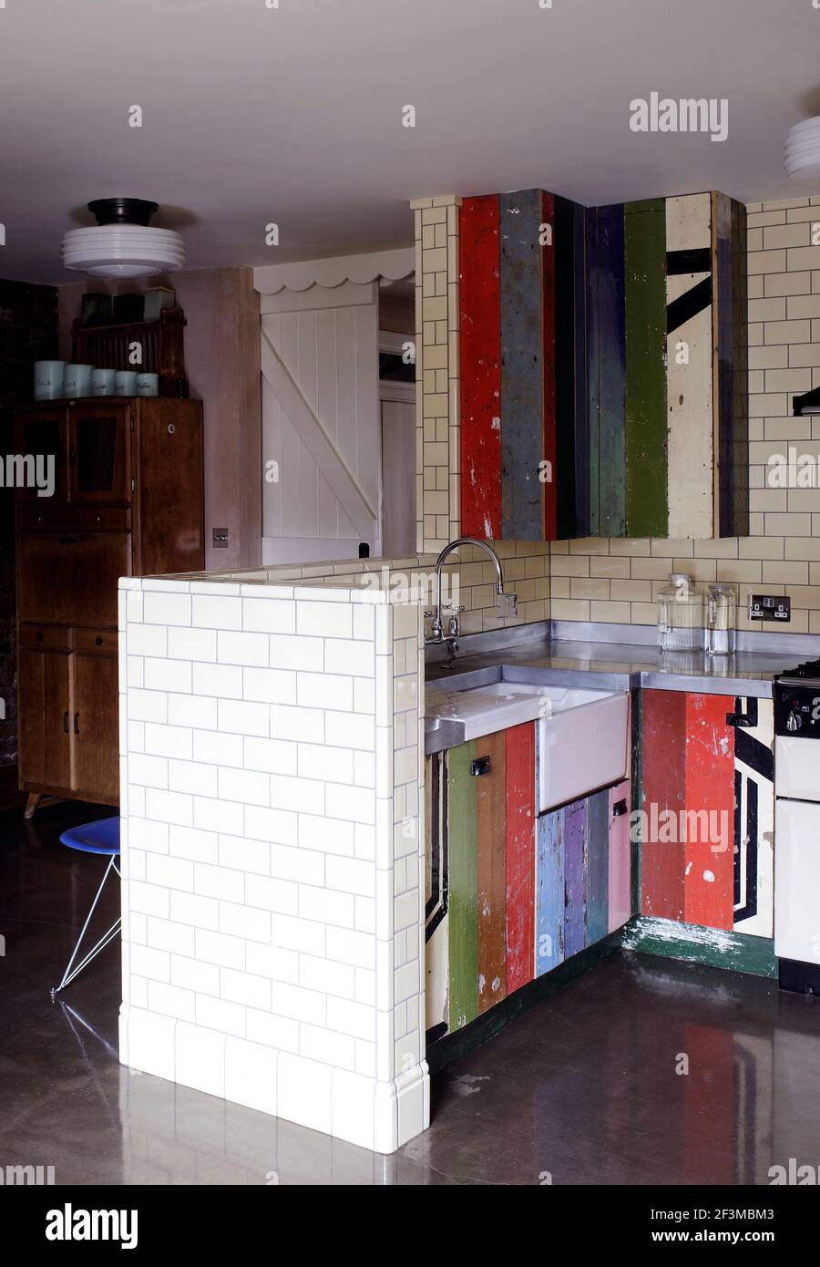 Open plan kitchen with tiled walls and multi coloured units in ...