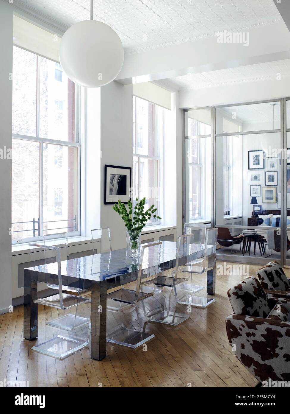 Reflective table and transparent chairs in large windowed living area ...