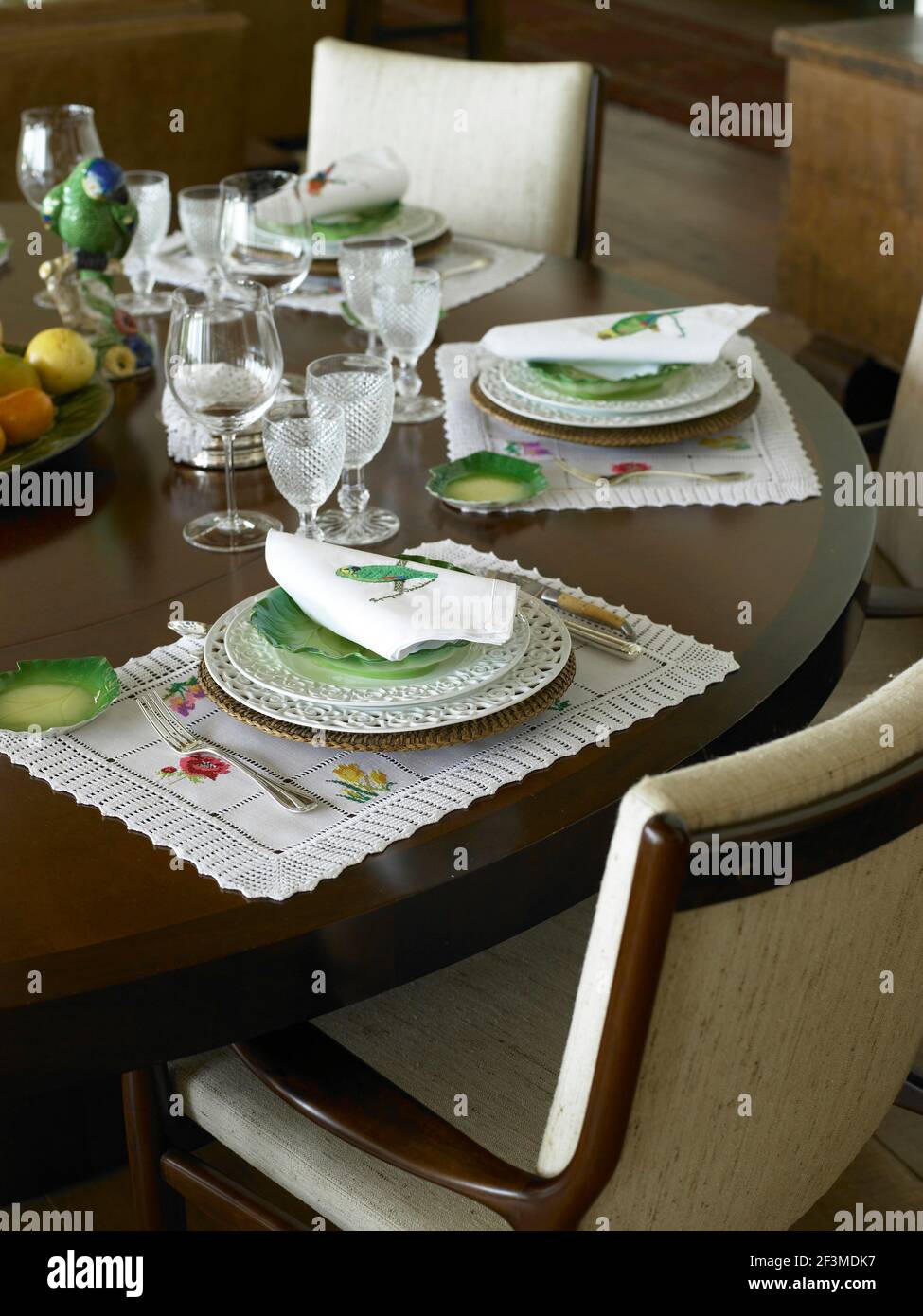 Parrot themed set table with plates and napkin on round dark wood table ...