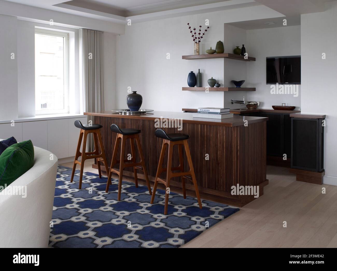 Alcove and flat screen TV with wooden breakfast bar and stools with ...