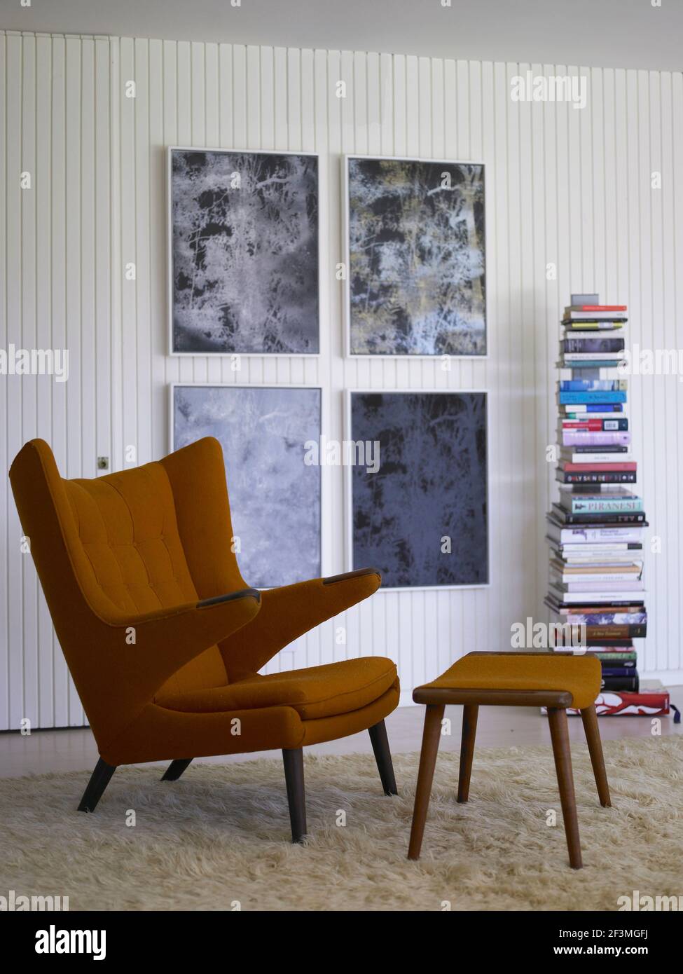 Vintage armchair and footstool with stack of books in California home ...
