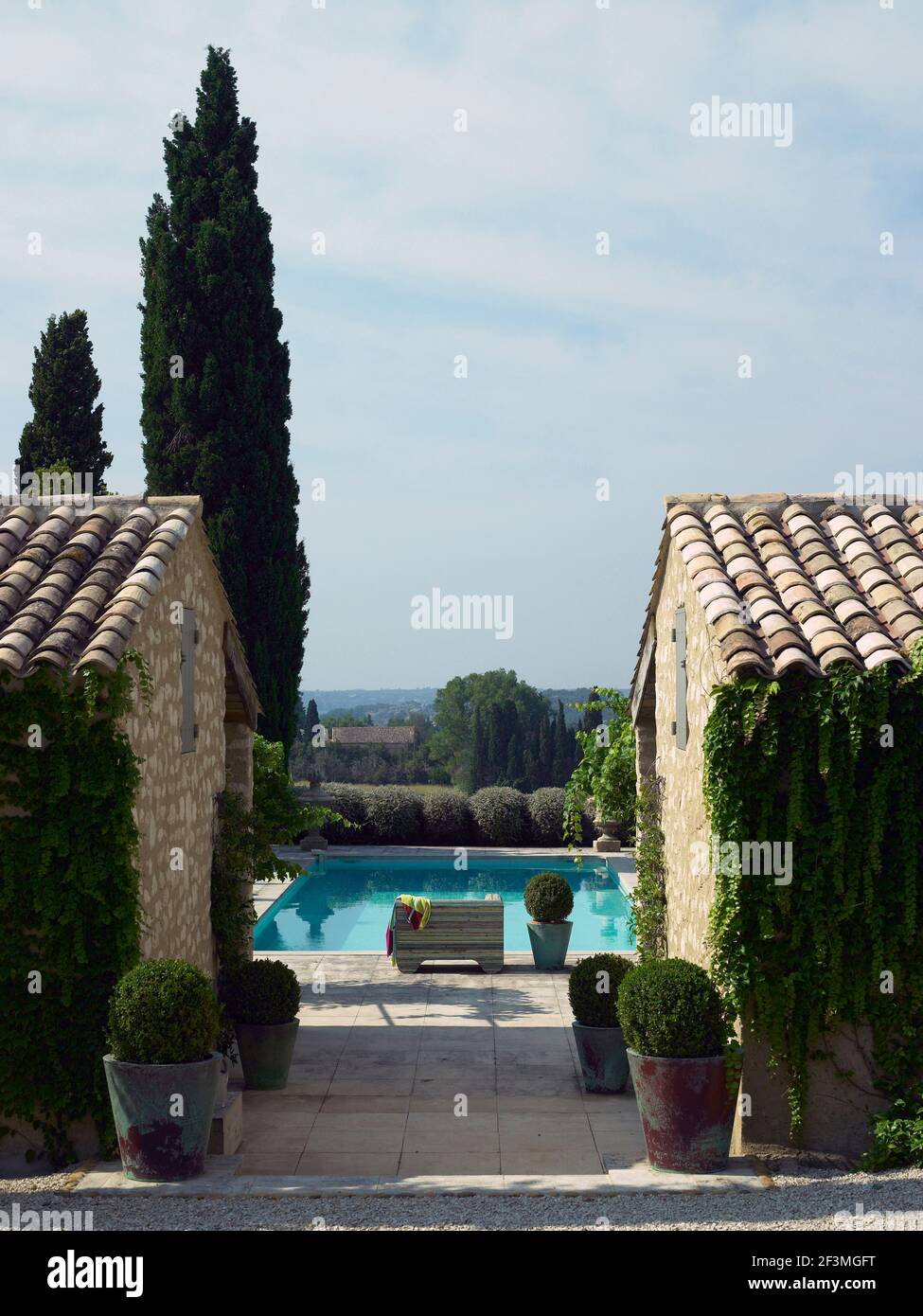 Swimming pool seen from between two tiled stone buildings, France Stock ...