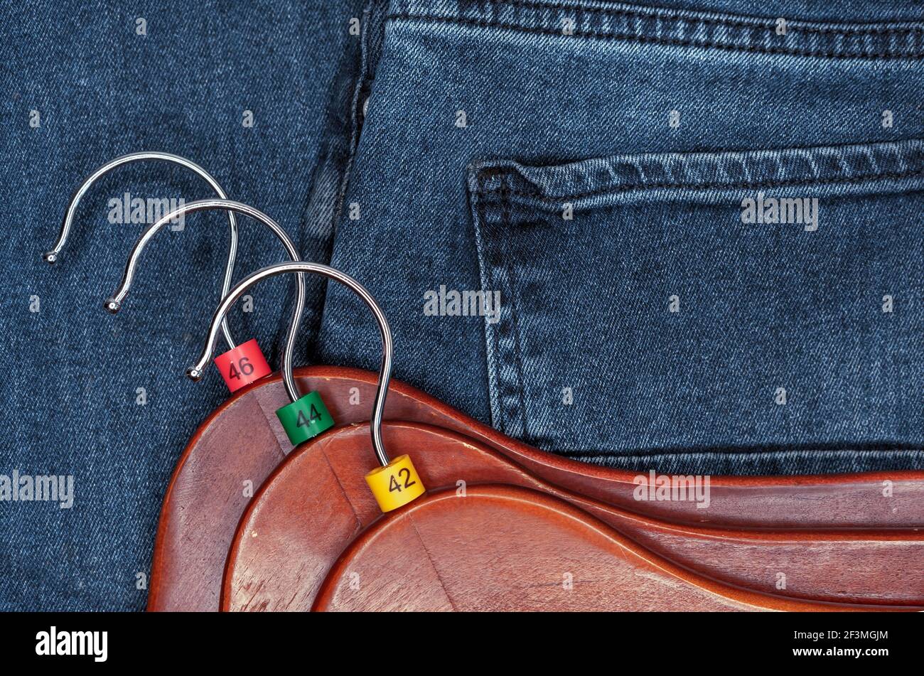 Clothes hangers with multicolored plastic size labels on a denim ...