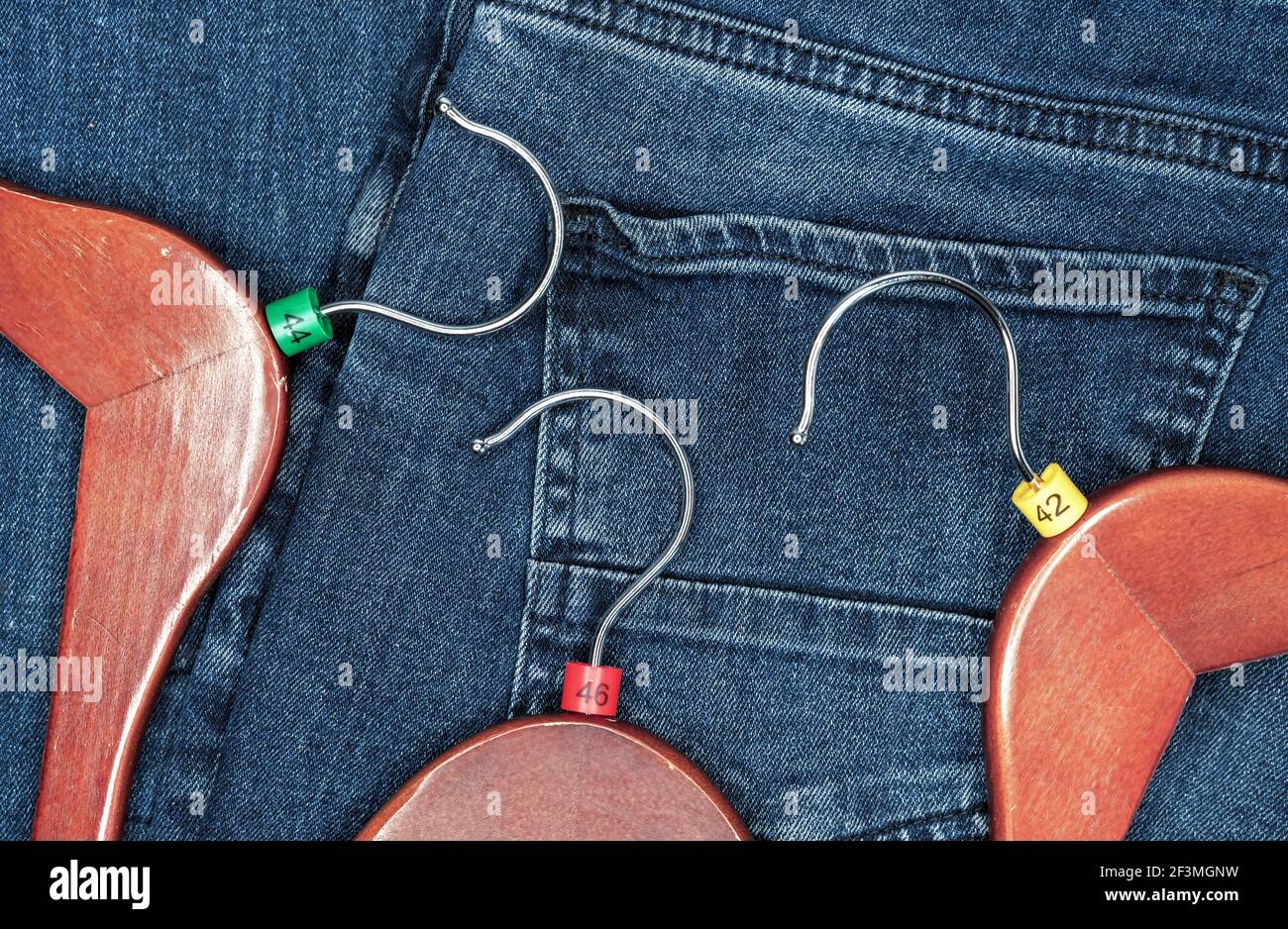 Clothes hangers with multicolored plastic size labels on a denim ...
