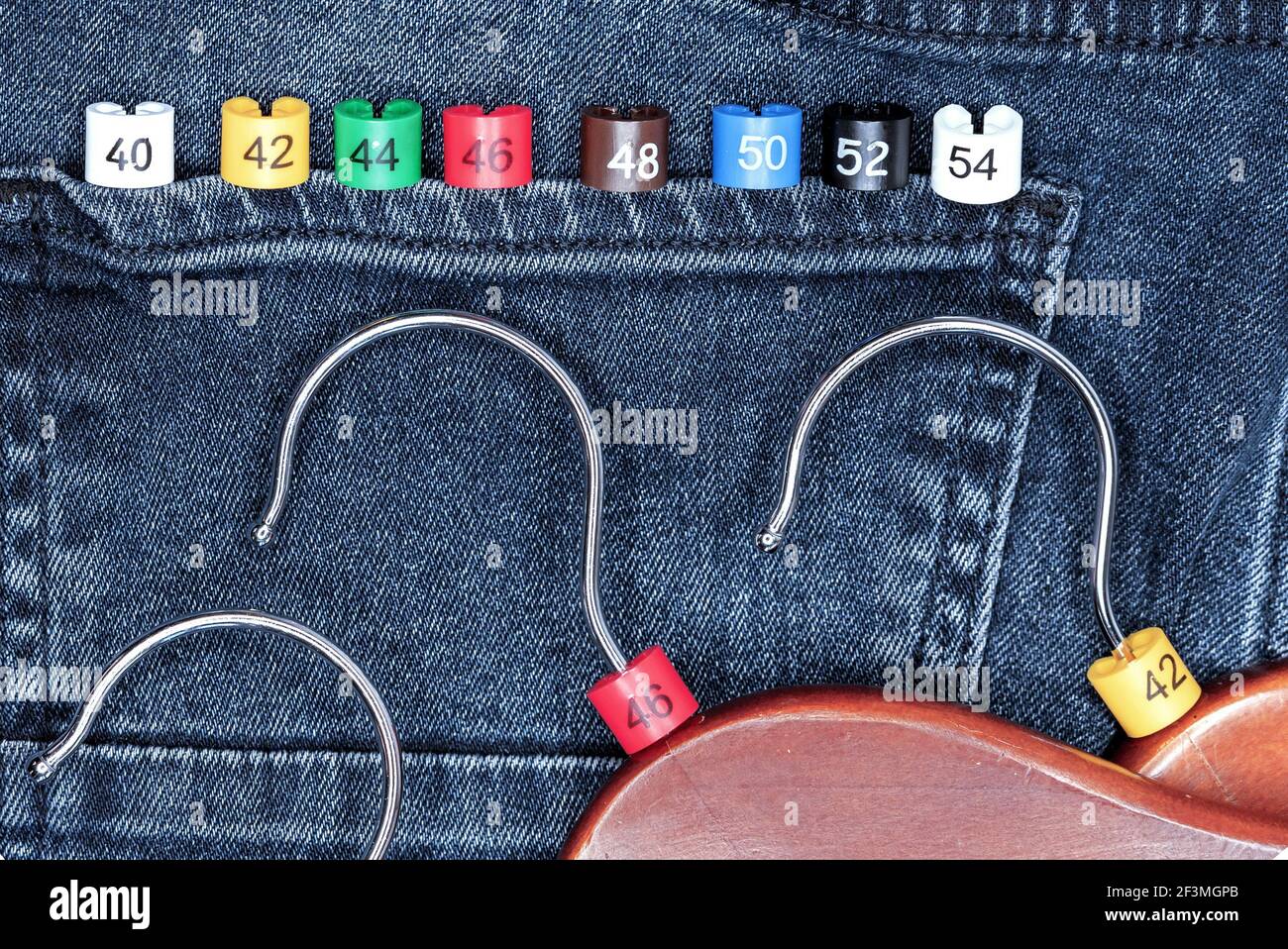 Clothes hangers with multicolored plastic size labels on a denim ...