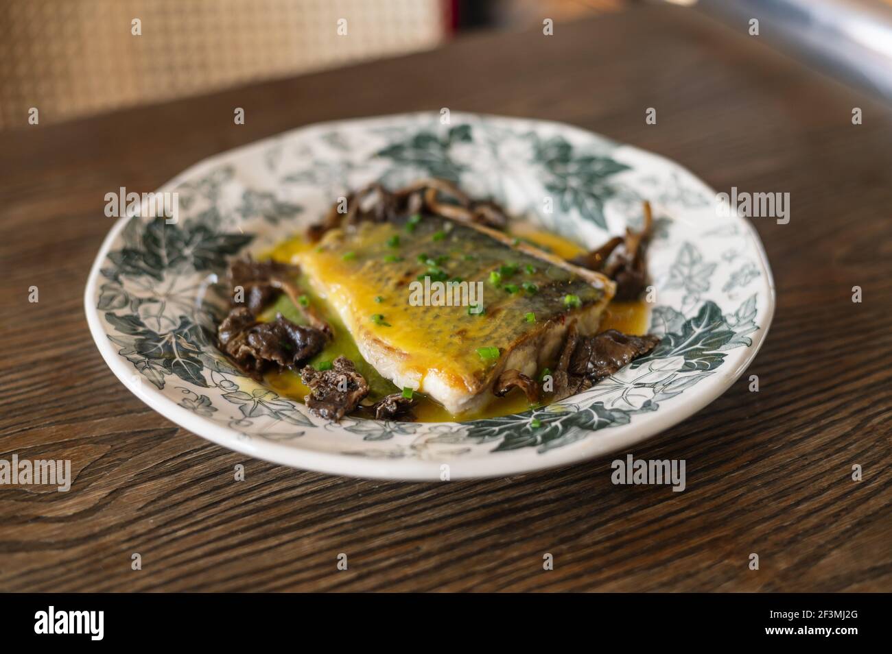 A closeup of a savory fish dish on a plate on a wooden table Stock ...