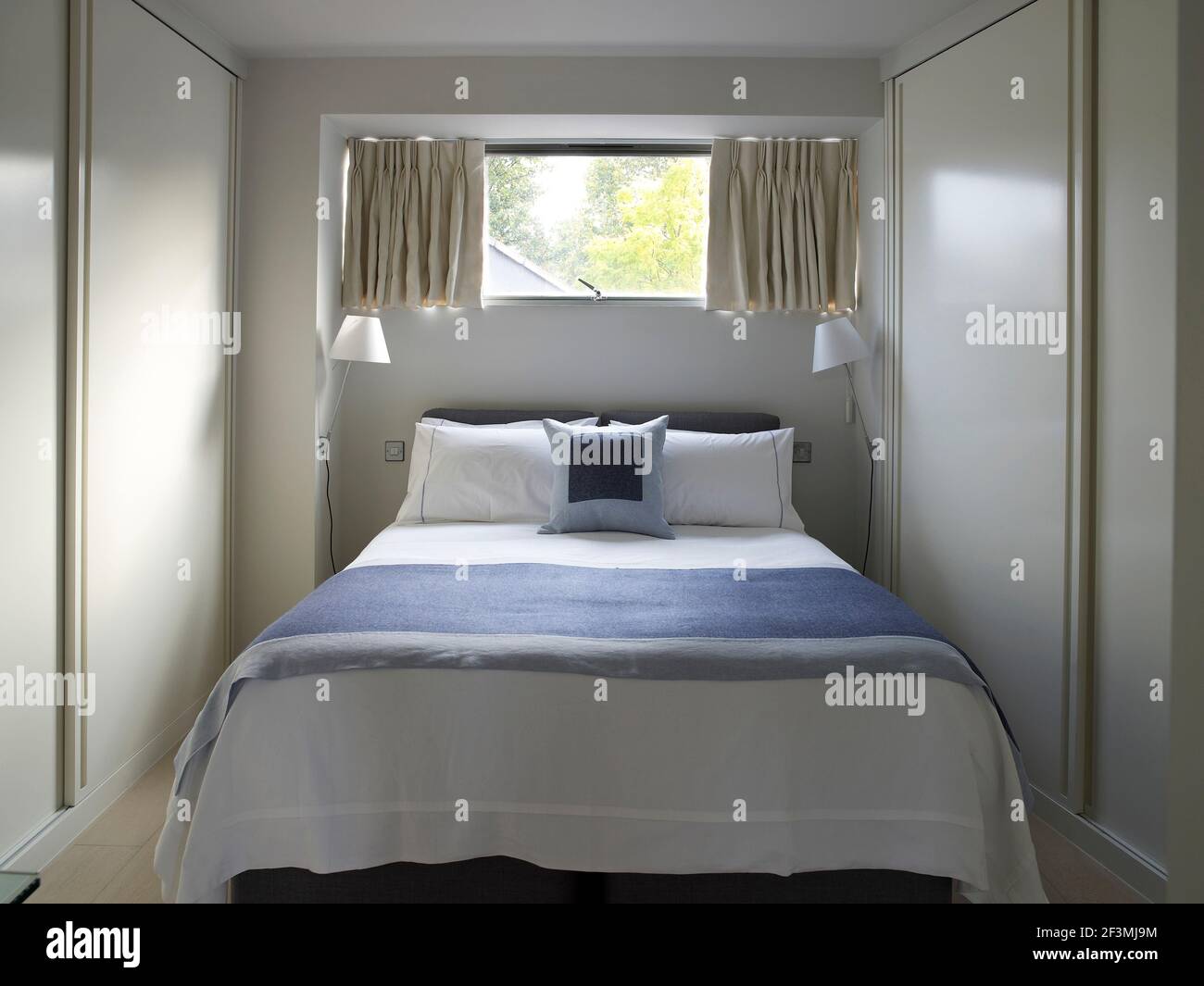 Double bed below window in room with sliding wardrobes in UK home Stock ...