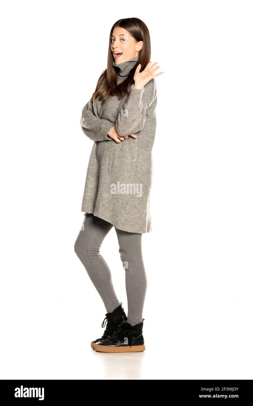 Side view of young beautiful woman in gray tunic waving hand on white ...