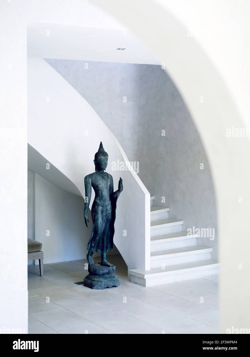 Eastern statue next to curving staircase in French home Stock Photo - Alamy