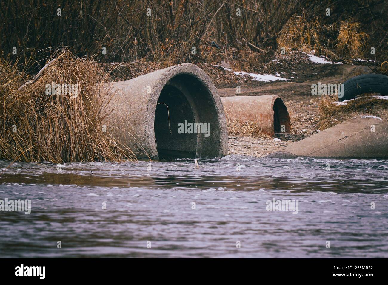 The water on the river flows from large pipes. Dam on the river Stock ...