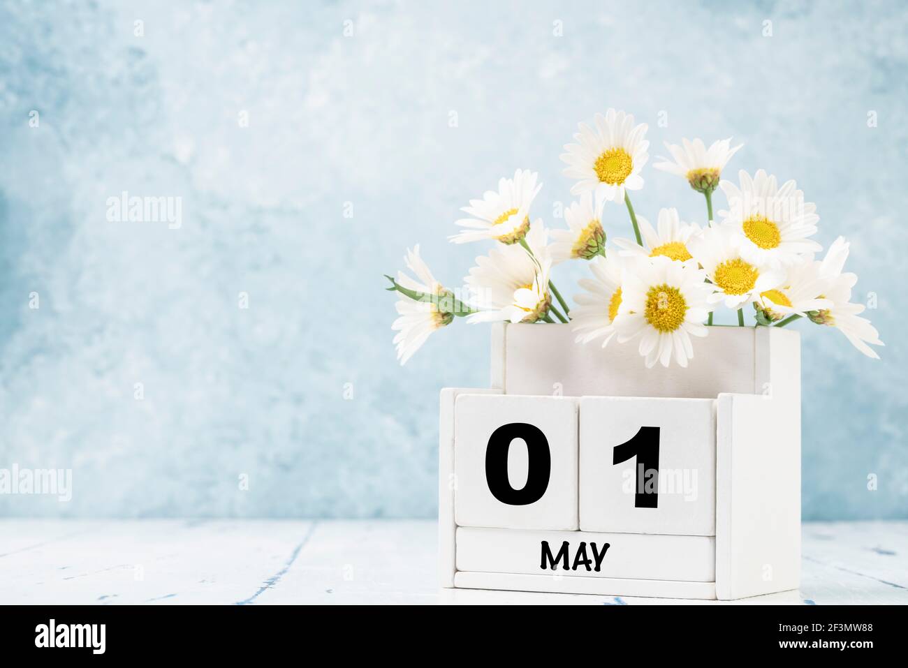 White cube calendar for May decorated with daisy flowers over blue ...