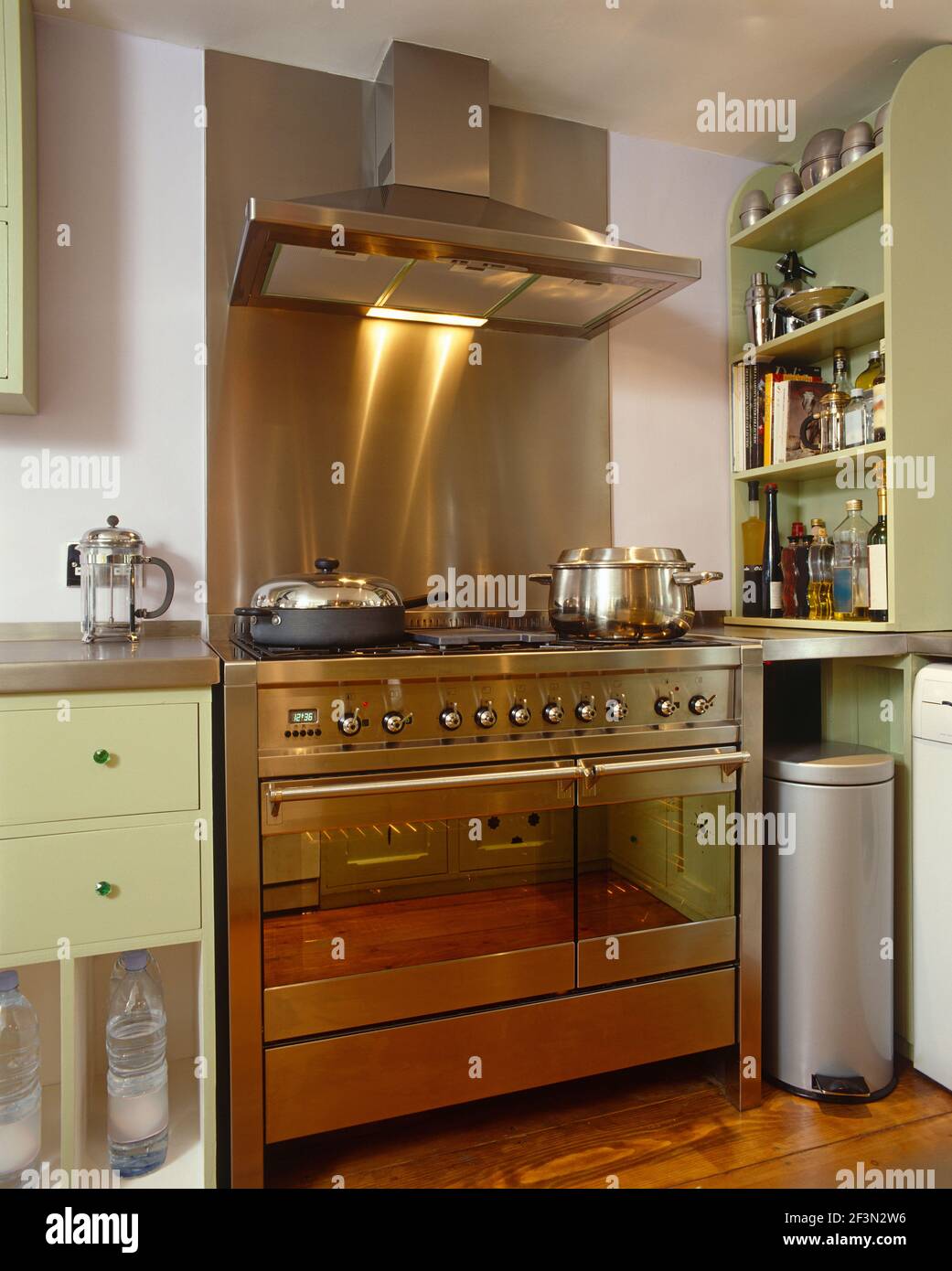 Kitchen with stainless steel range cooker and light green units Stock ...