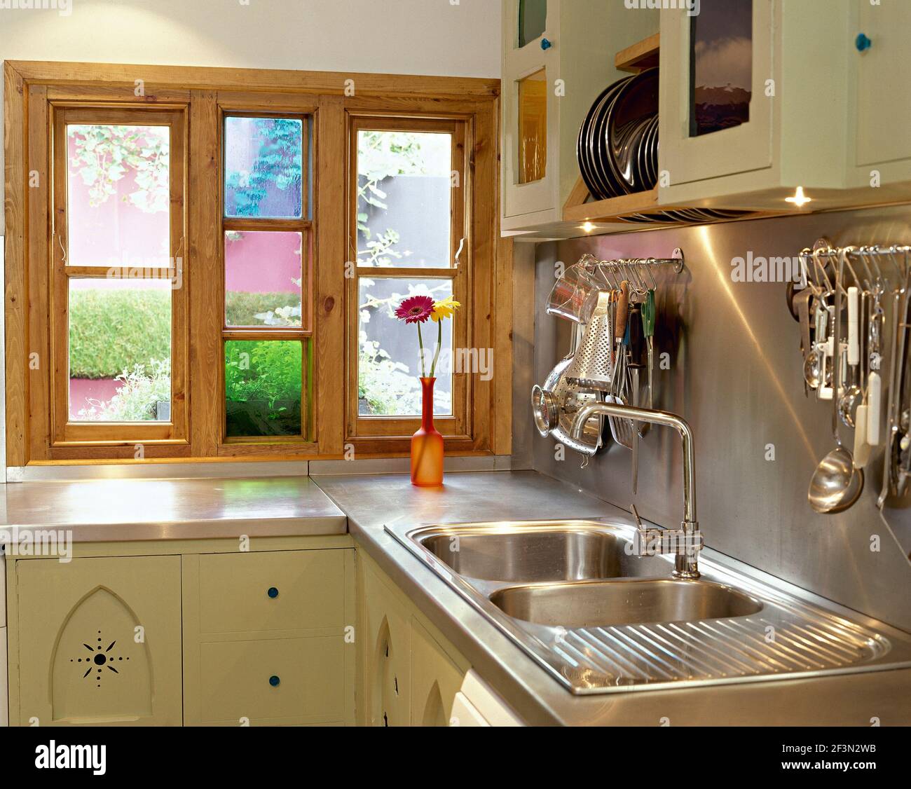 Kitchen with stainless steel sink and splashback and hanging utensils ...