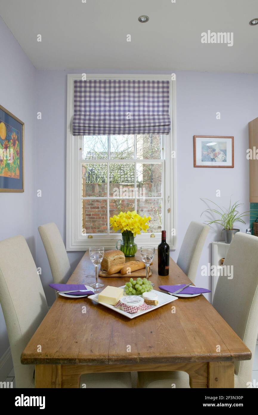 Pine table set for lunch next to window dressed with blue check pattern ...