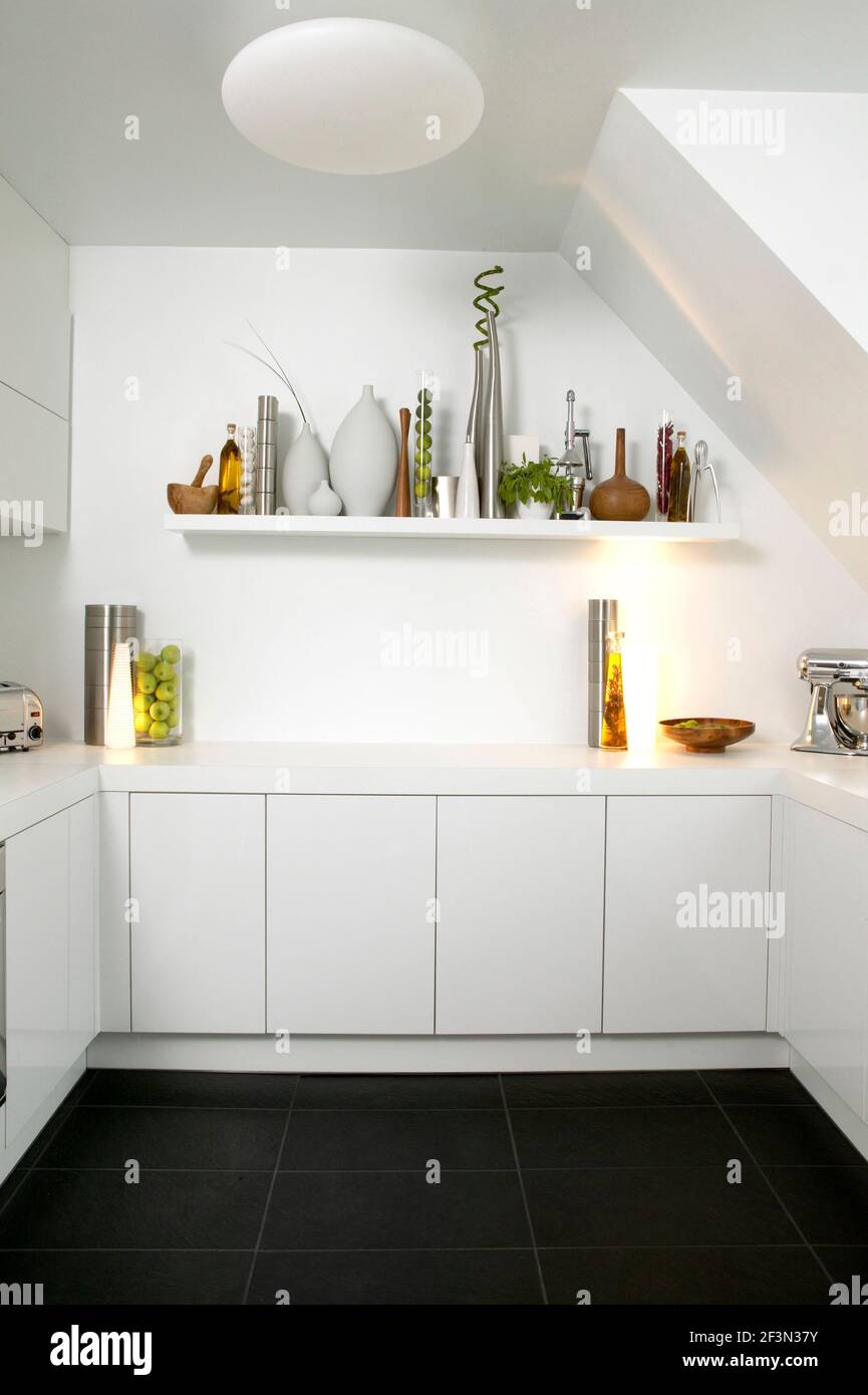 Minimalist kitchen with white fitted units and shelving above Stock ...