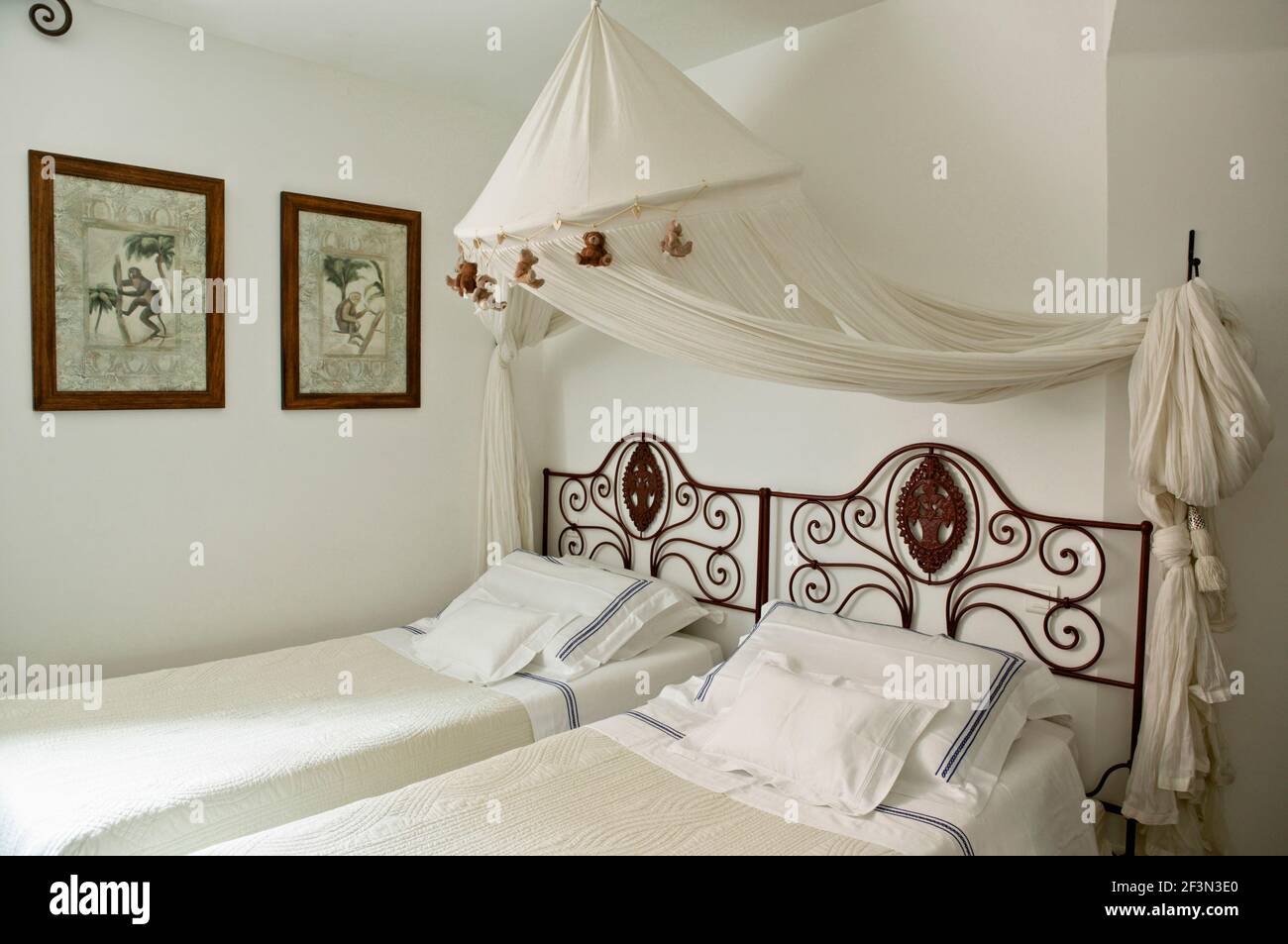 Canopy above two single beds in white bedroom Stock Photo - Alamy