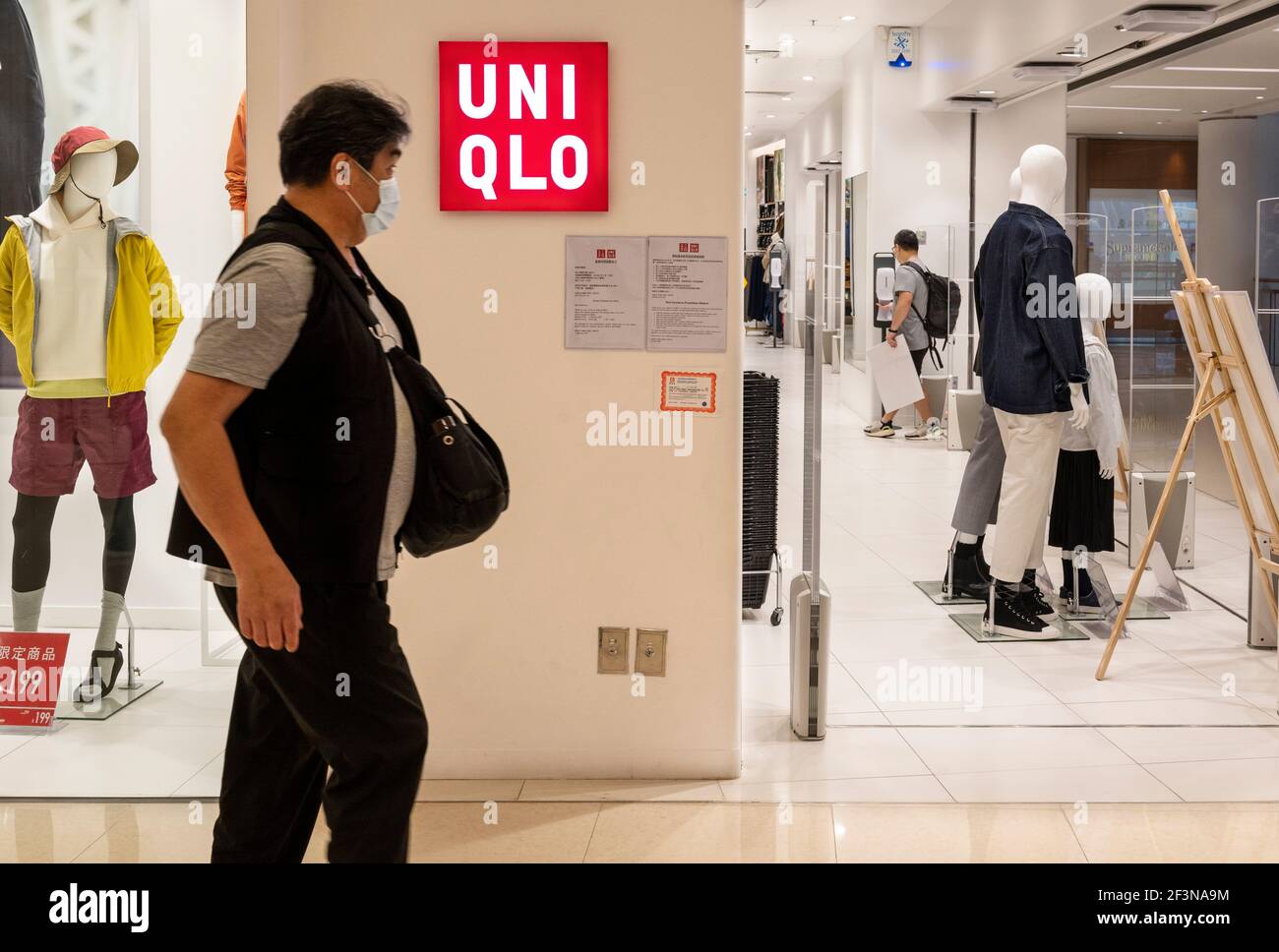 A man walks past the Japanese clothing brand Uniqlo logo and store in ...