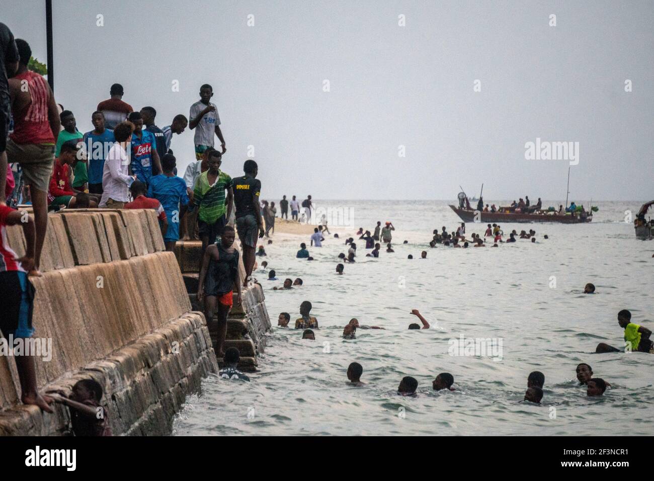 Stone Town, Zanzibar, Tanzania - January 2020: Locals run and jump into ...