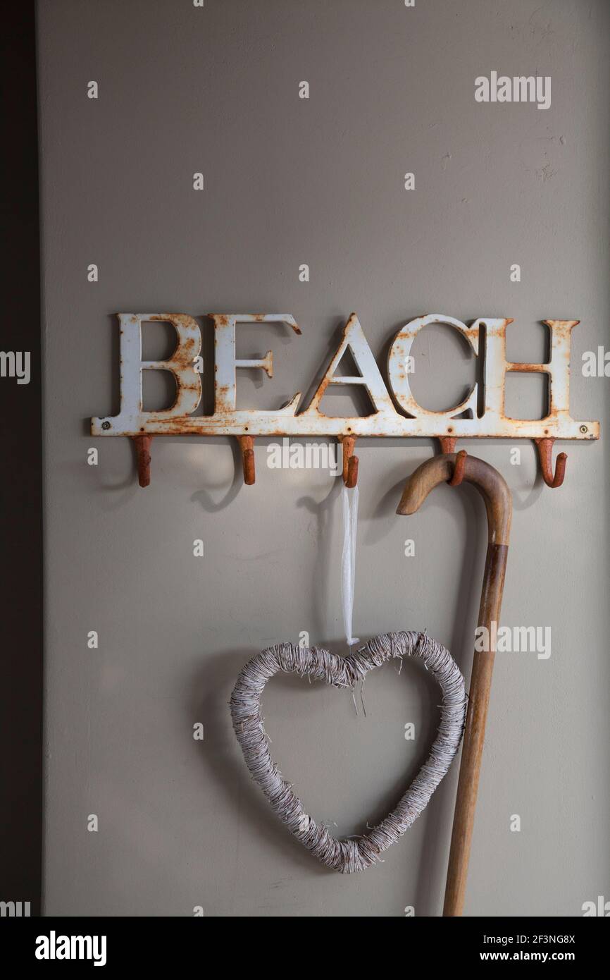 Rusty beach named hat rack with white straw heart decoration and wooden ...