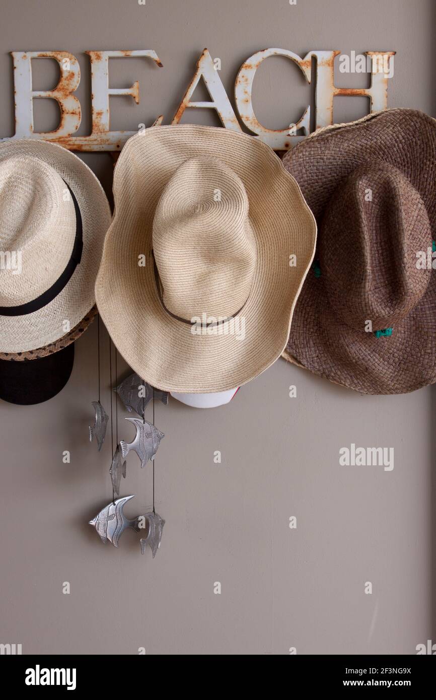 Rusty beach named hat rack with straw beach hats and silver fish wind ...