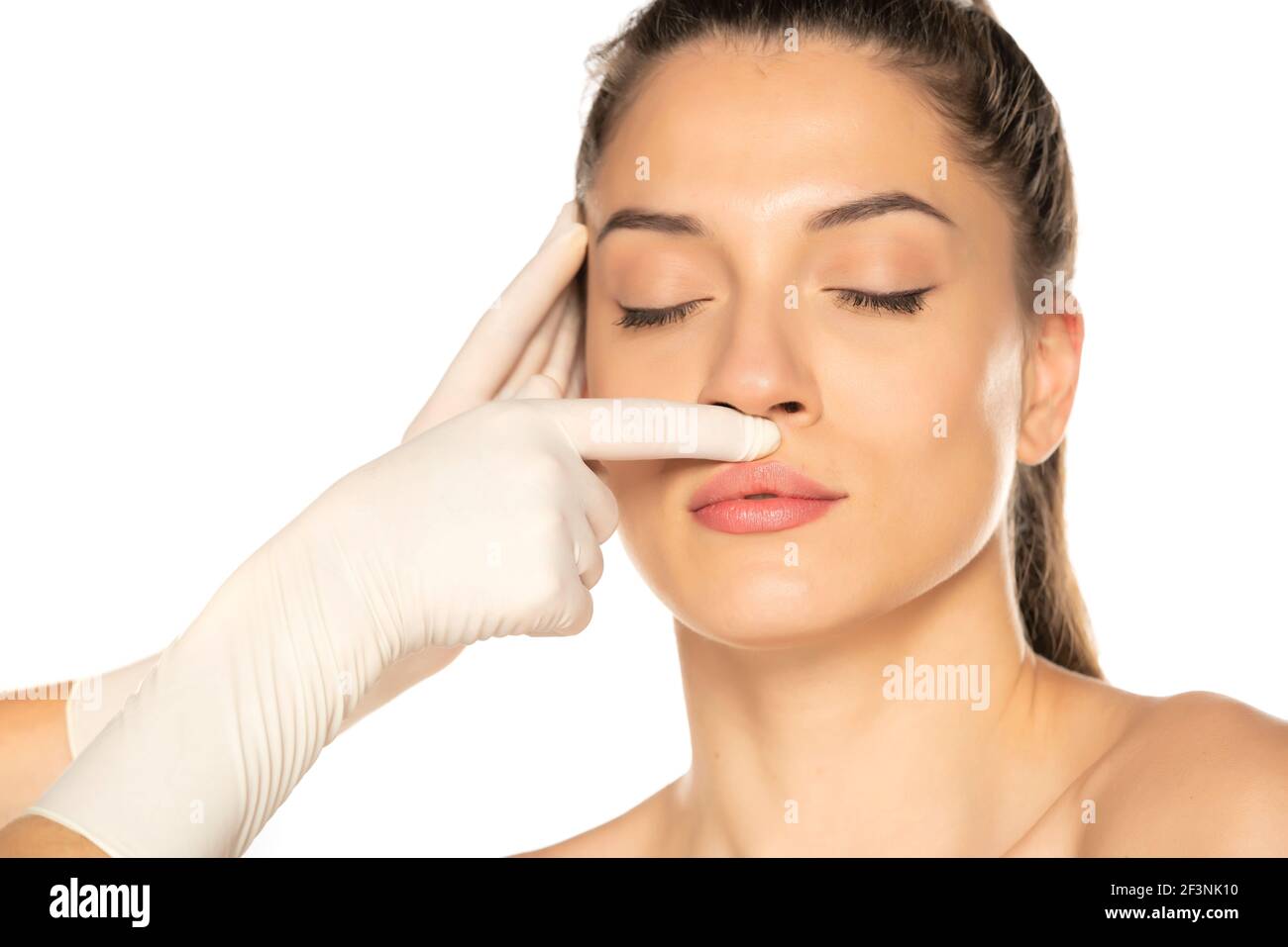 doctor's hands in gloves checks the face of young woman on white ...
