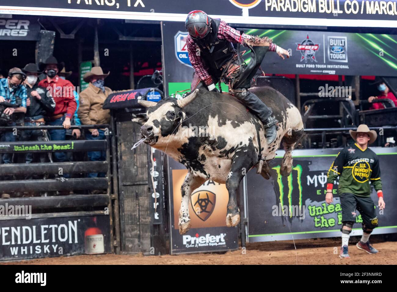 Professional bull rider flying high on a bull while trying to stay on ...