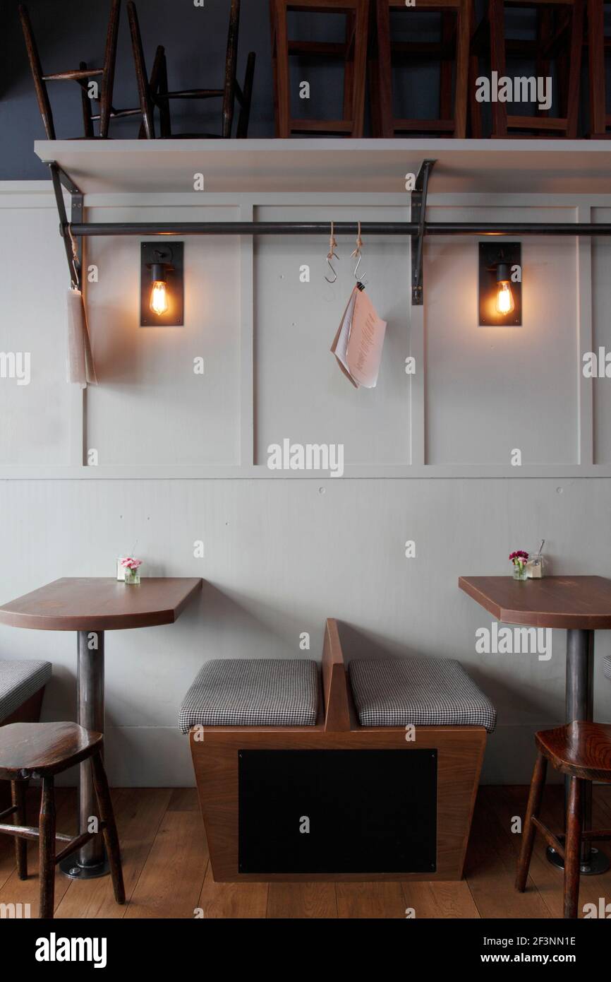 Built in seating and tables along wall with extra stools stored above ...