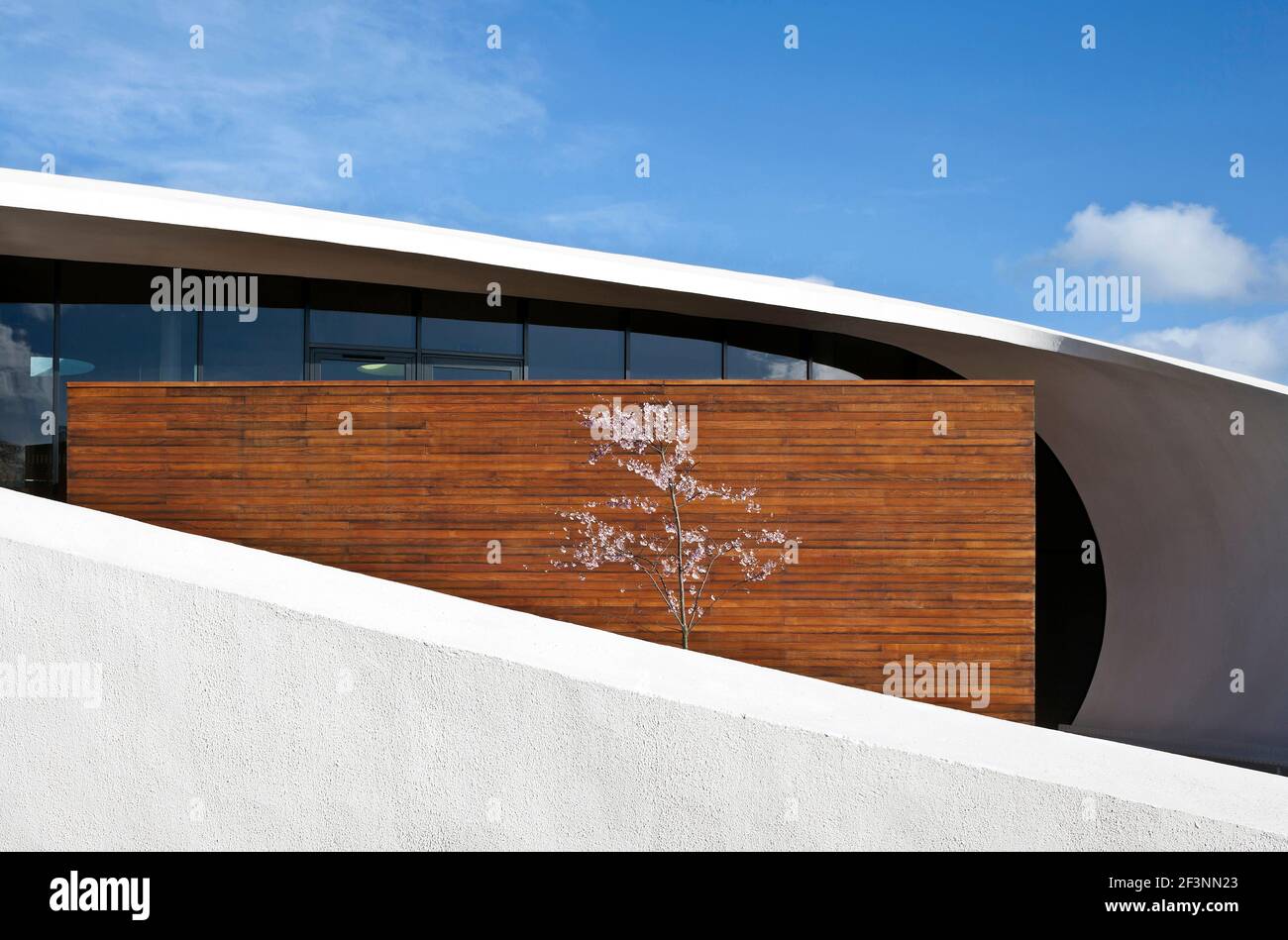 A dramatic white curved outer structure around a building which offers ...