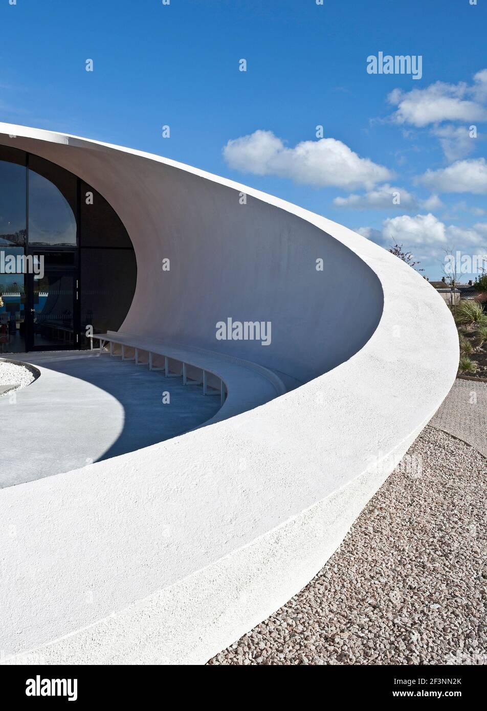 A dramatic white curved outer structure around a building which offers ...