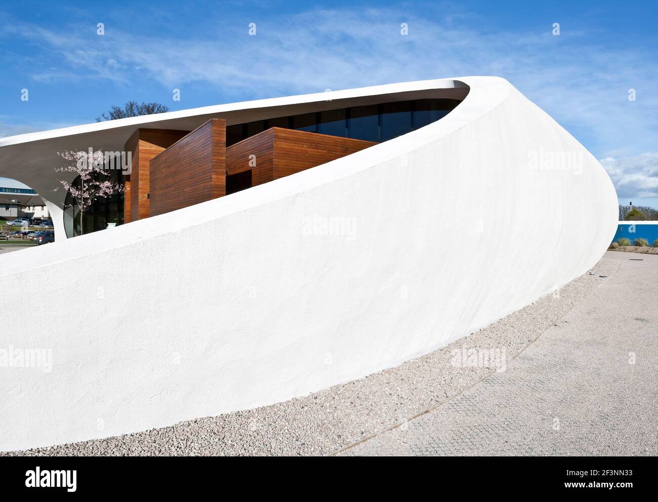A dramatic white curved outer structure around a building which offers ...
