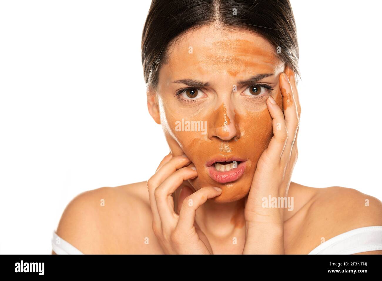 Young disappointed woman with wrong makeup base on her face on white ...