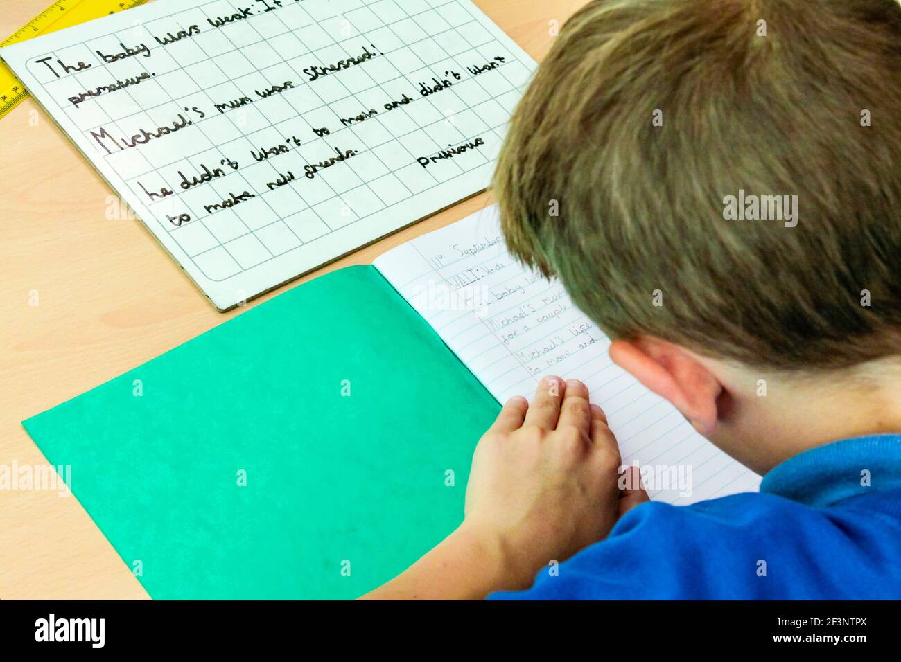 Primary school child writing on a desk during a lesson Stock Photo - Alamy