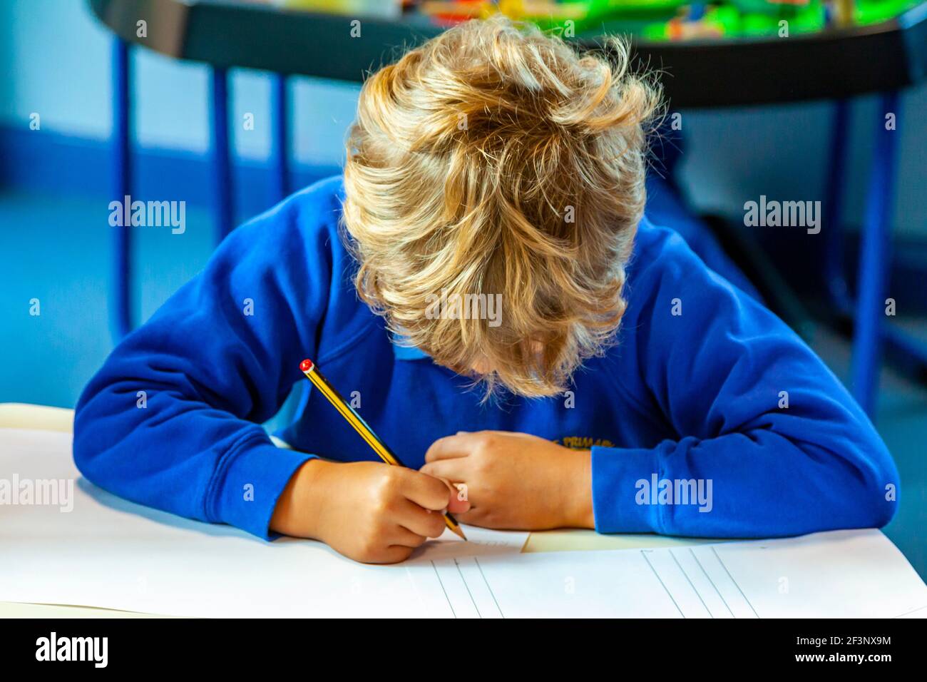 Primary school child writing on a desk during a lesson Stock Photo - Alamy
