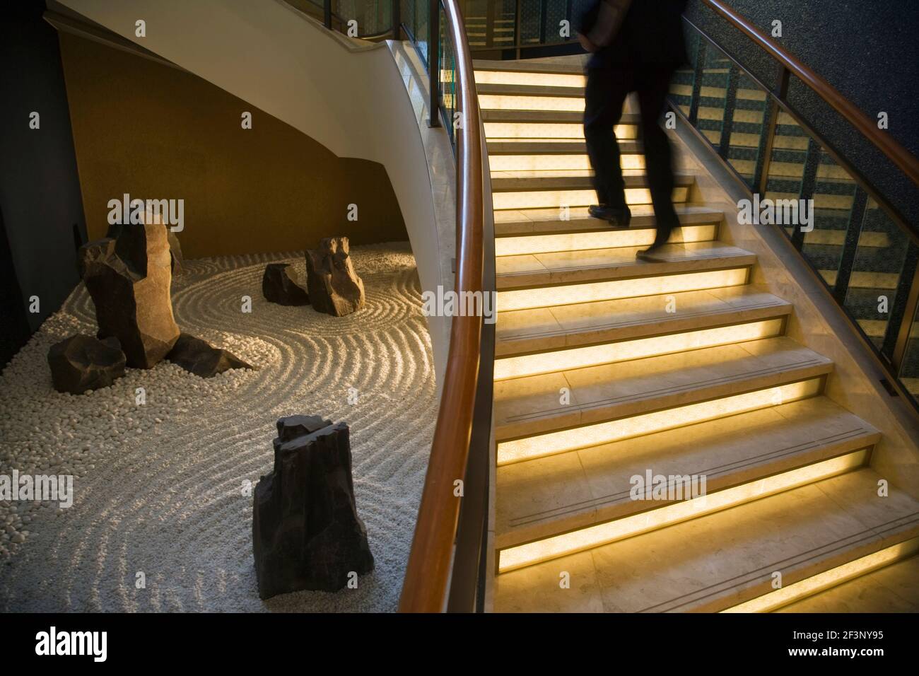 A gracefully winding staircase rises from a small zen-style rock garden ...