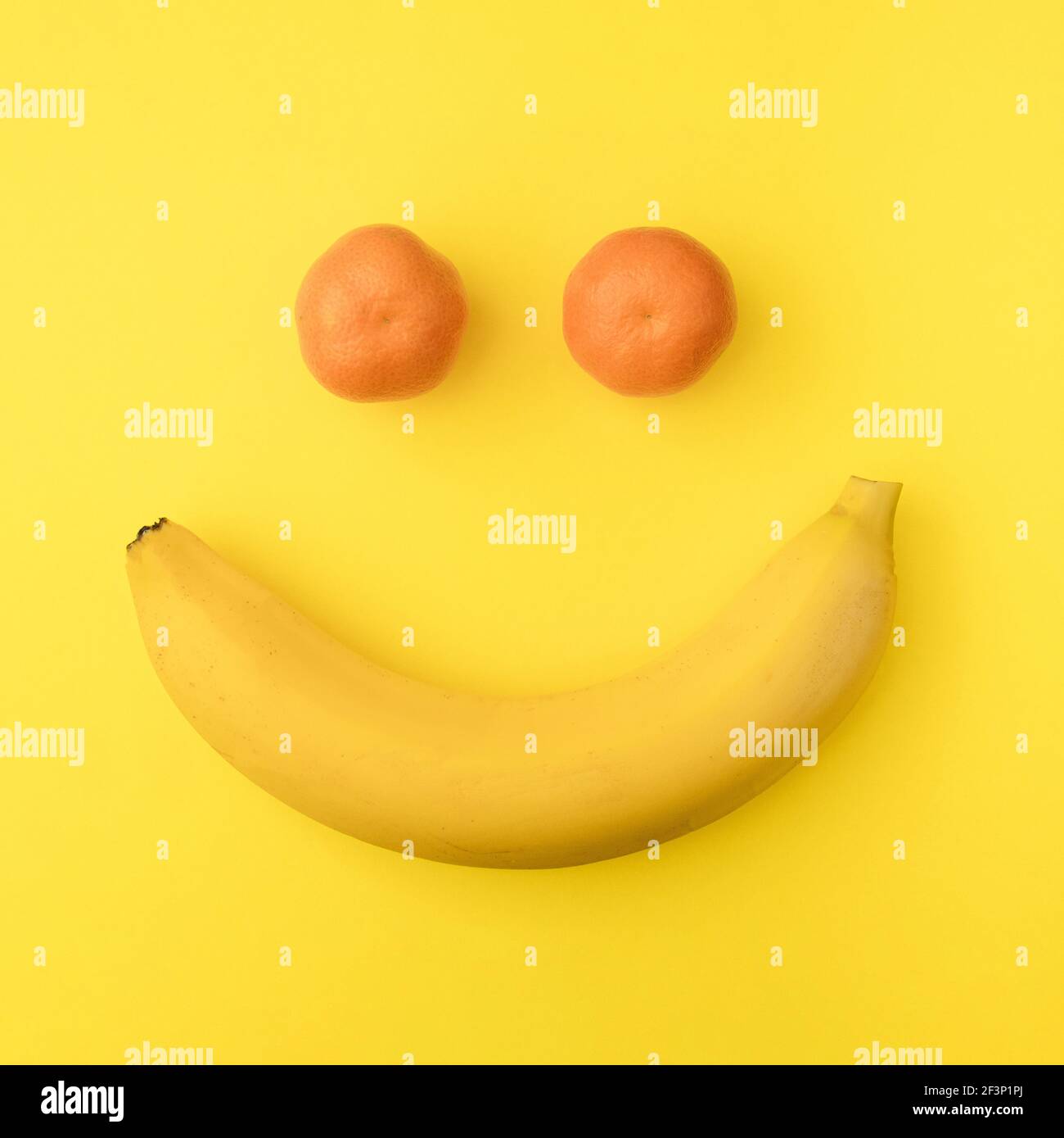Positive smiley face from banana and tangerine on a yellow background ...