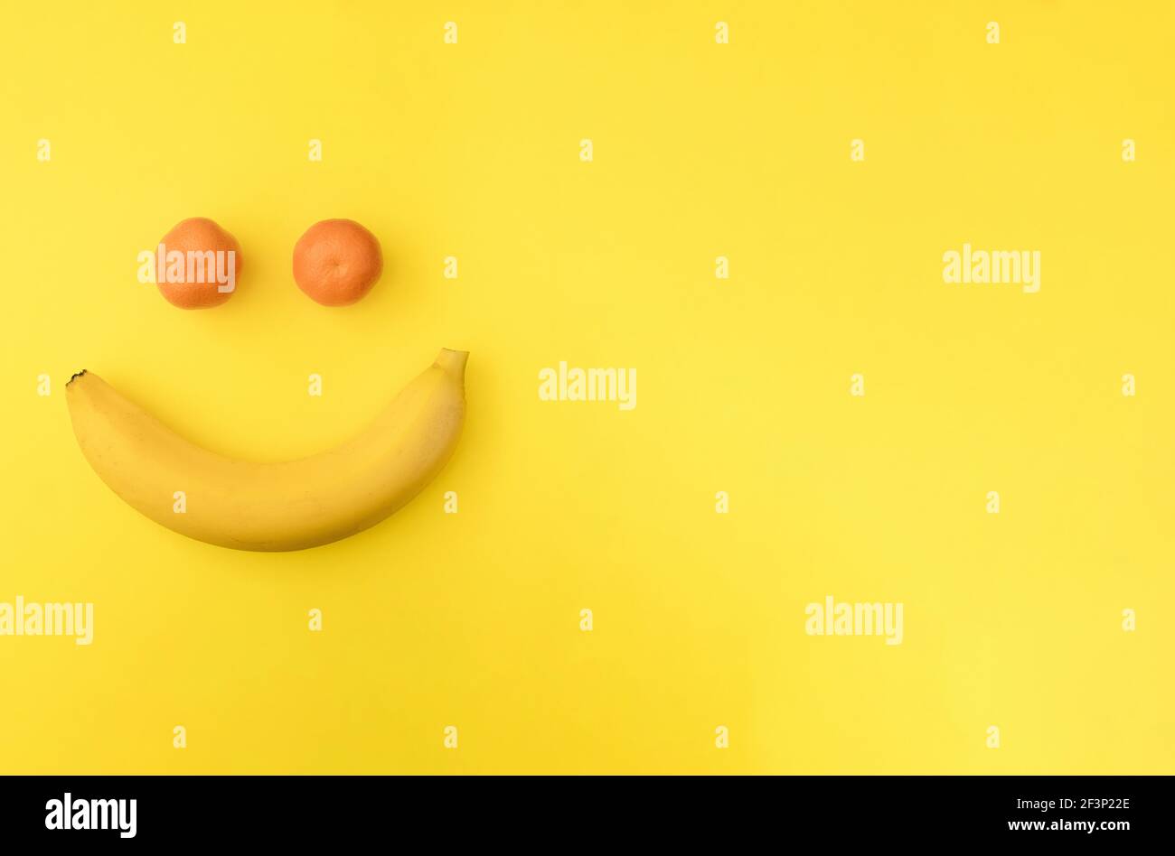 Positive smiley face from banana and tangerine on a yellow background ...