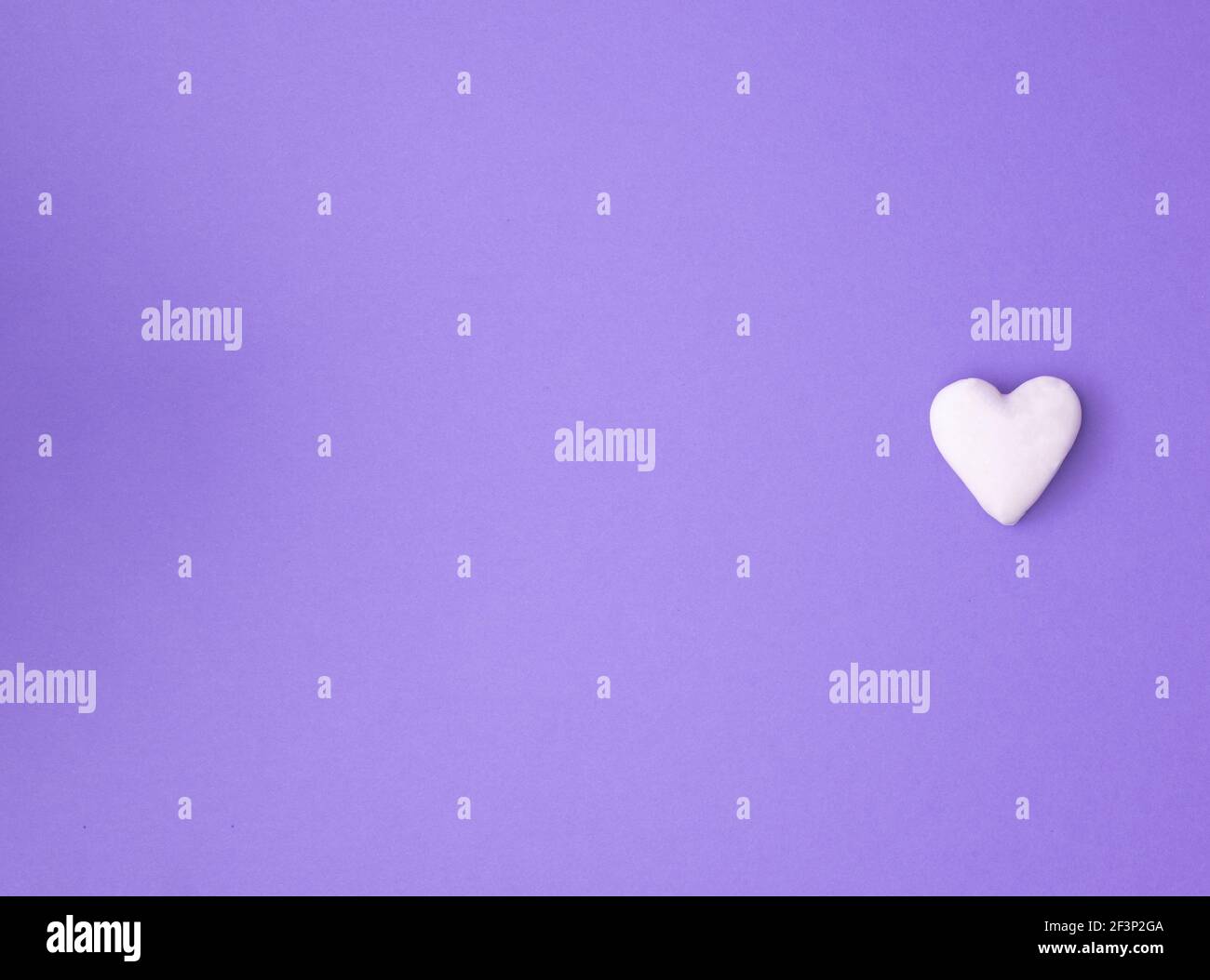 Creative love idea with small white heart on purple background with ...