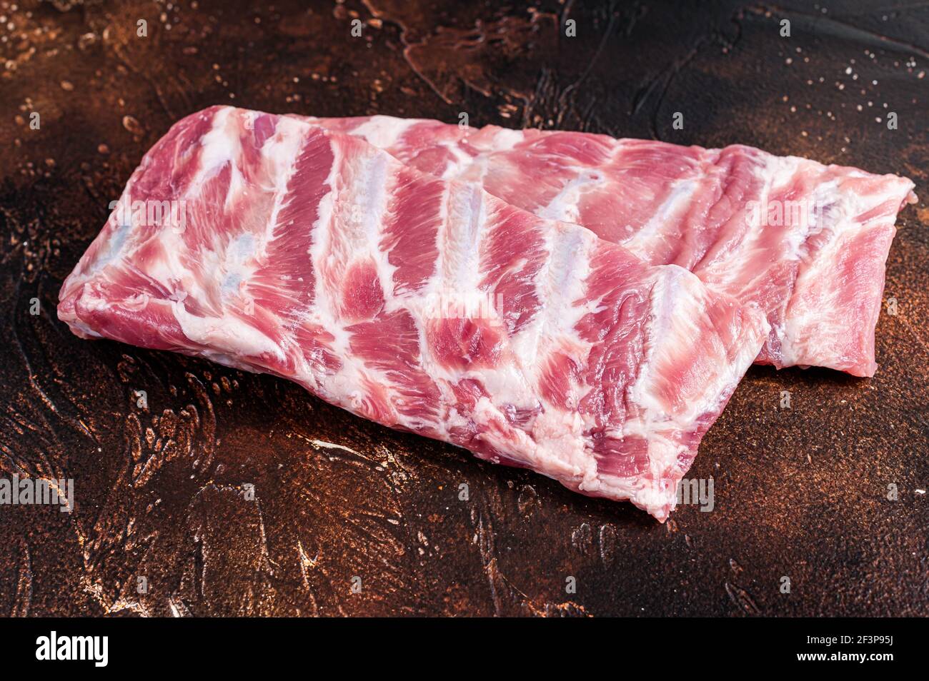 Rack of raw pork spare ribs on butcher table. Dark background. Top view ...