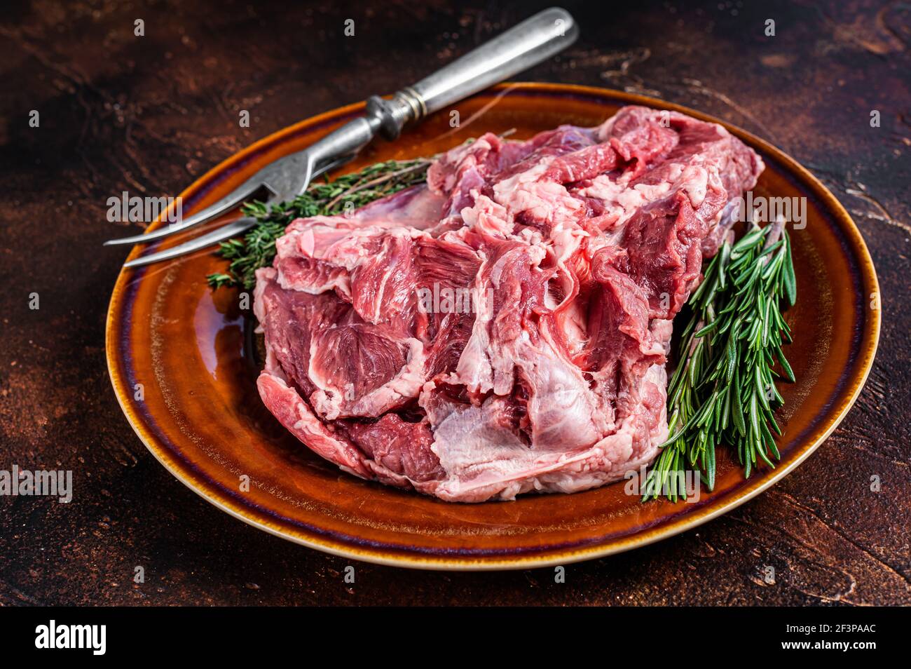 Raw Boneless Lamb leg meat in rustic plate with thyme. Dark background ...