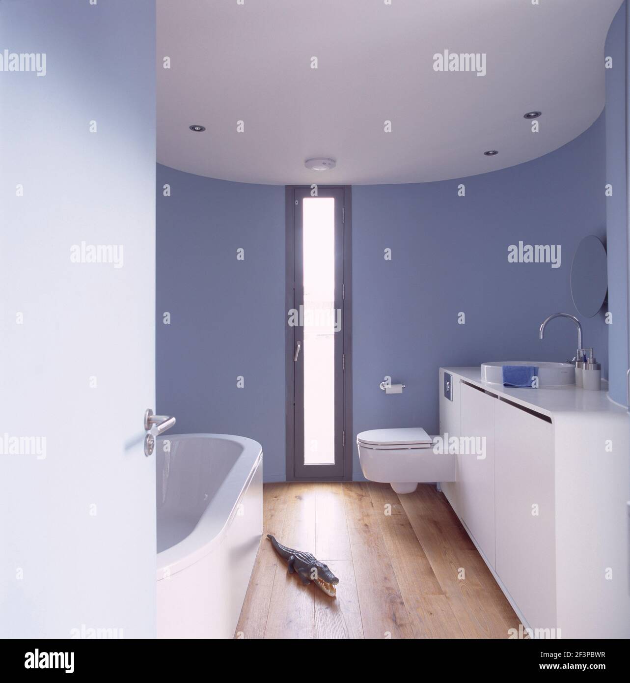Cool blue bathroom with washbasin set on cupboard unit and bathtub ...