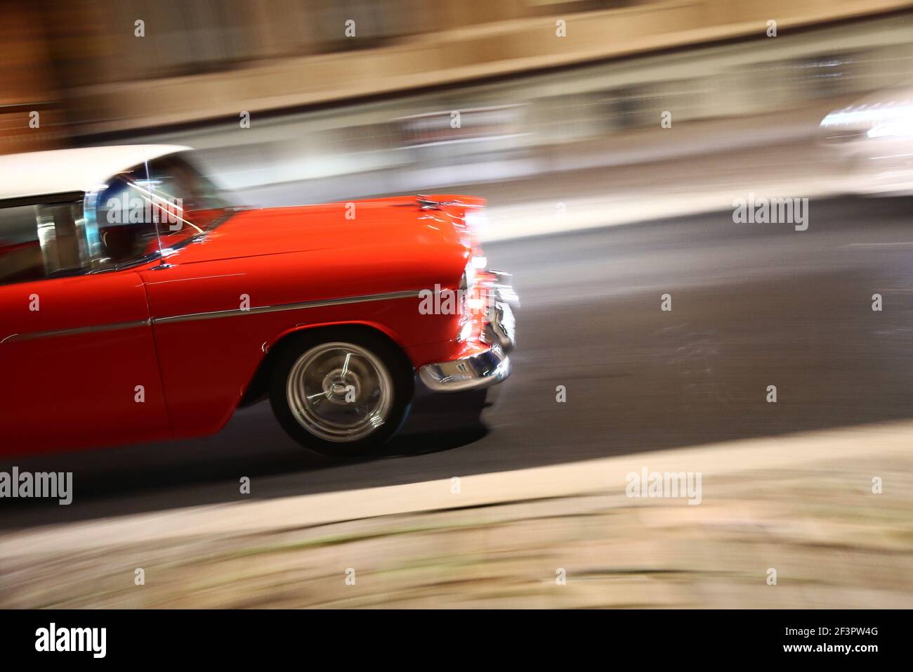 Car parade with American vintage cars through a city one evening in ...