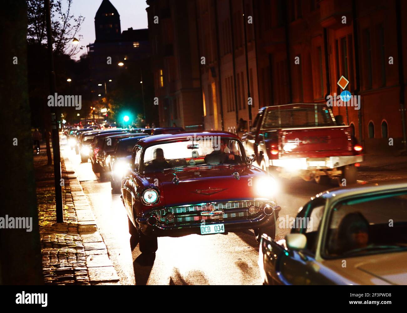 Car parade with American vintage cars through a city one evening in ...