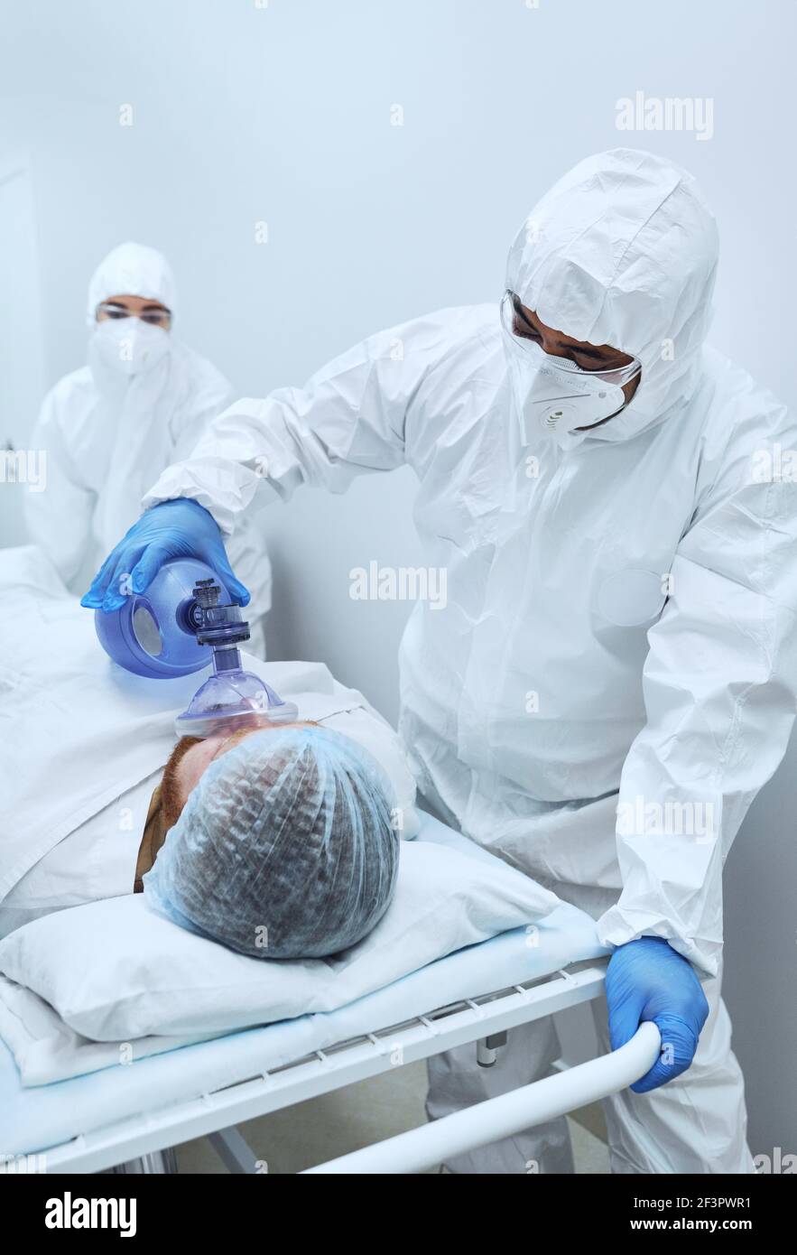 Surgeons in uniform using oxygen mask for male patient in operating ...