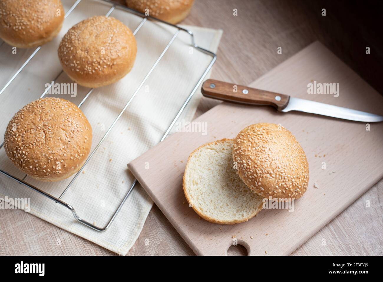 Cooking at home, sesame hamburger bun cut in half on a board in the ...