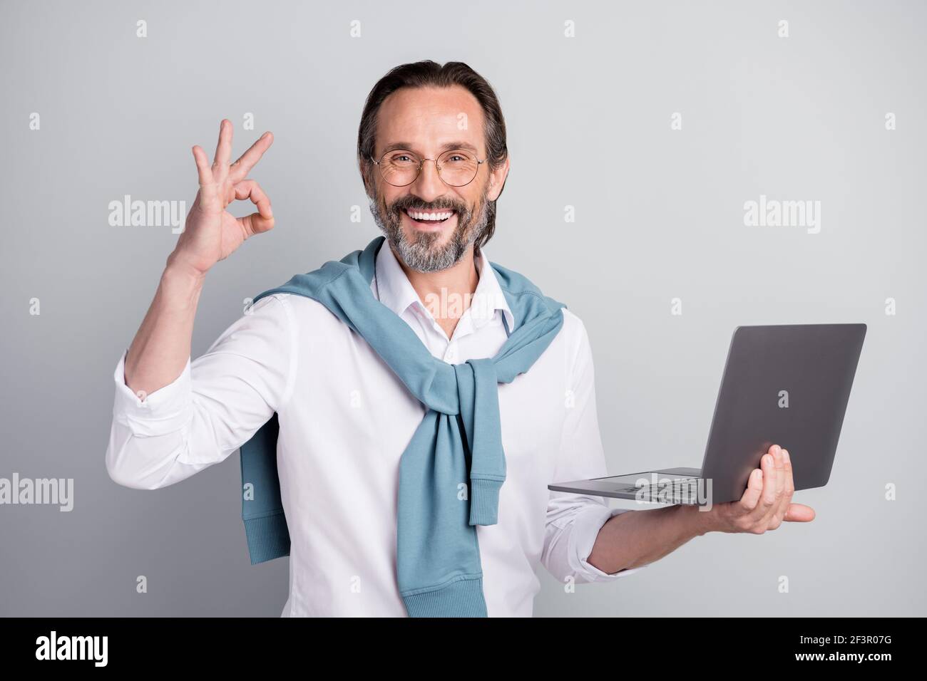 Photo portrait of happy man holding computer smiling showing okay ...